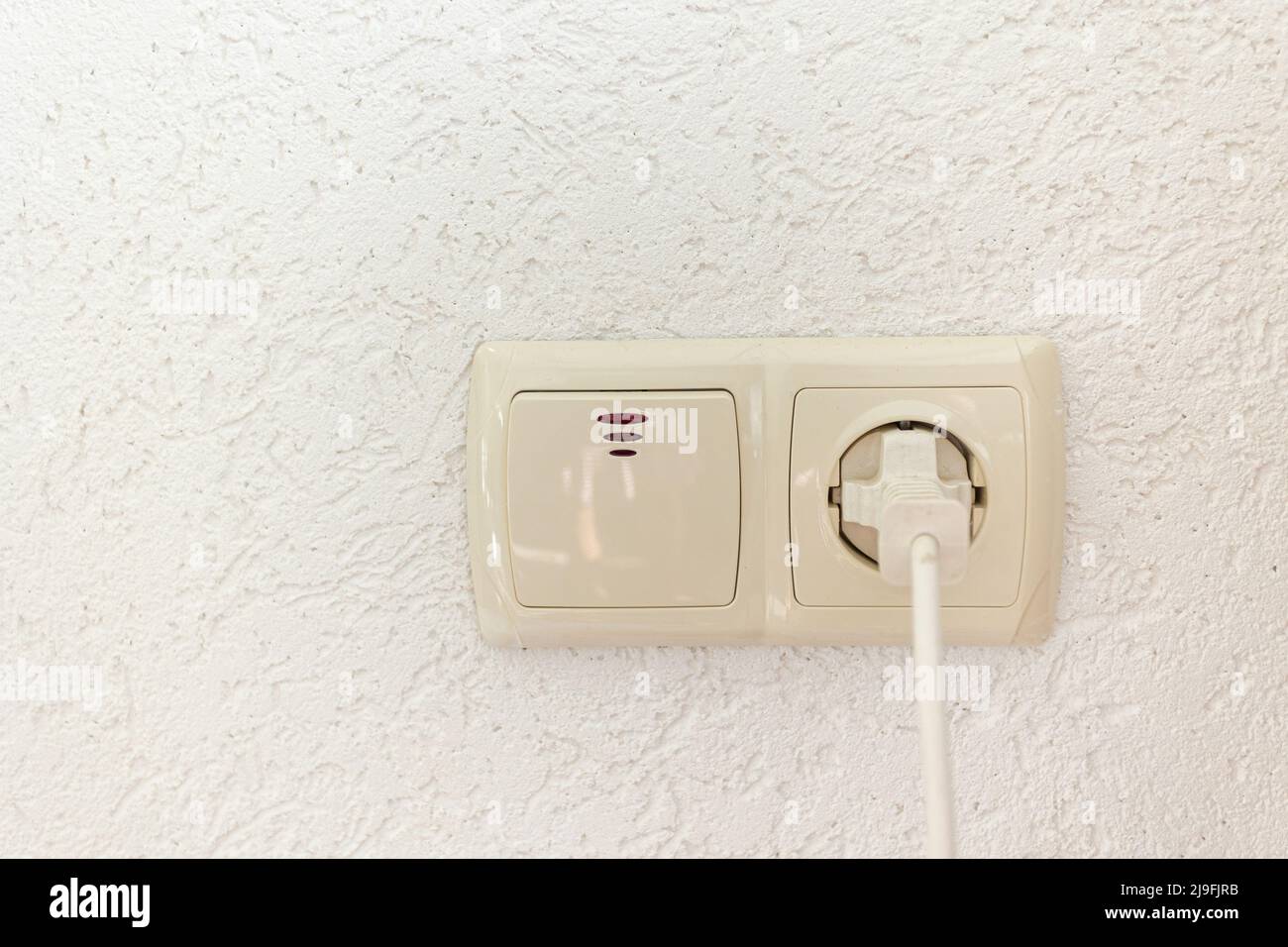 white socket with plug and light switch on an empty wall Stock Photo ...