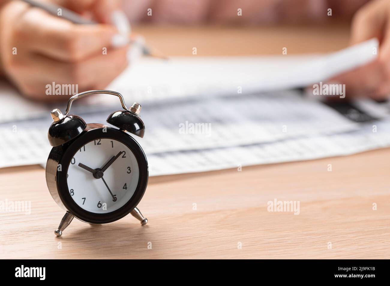 alarm clock with time running out. Students hands to take exams, write ...