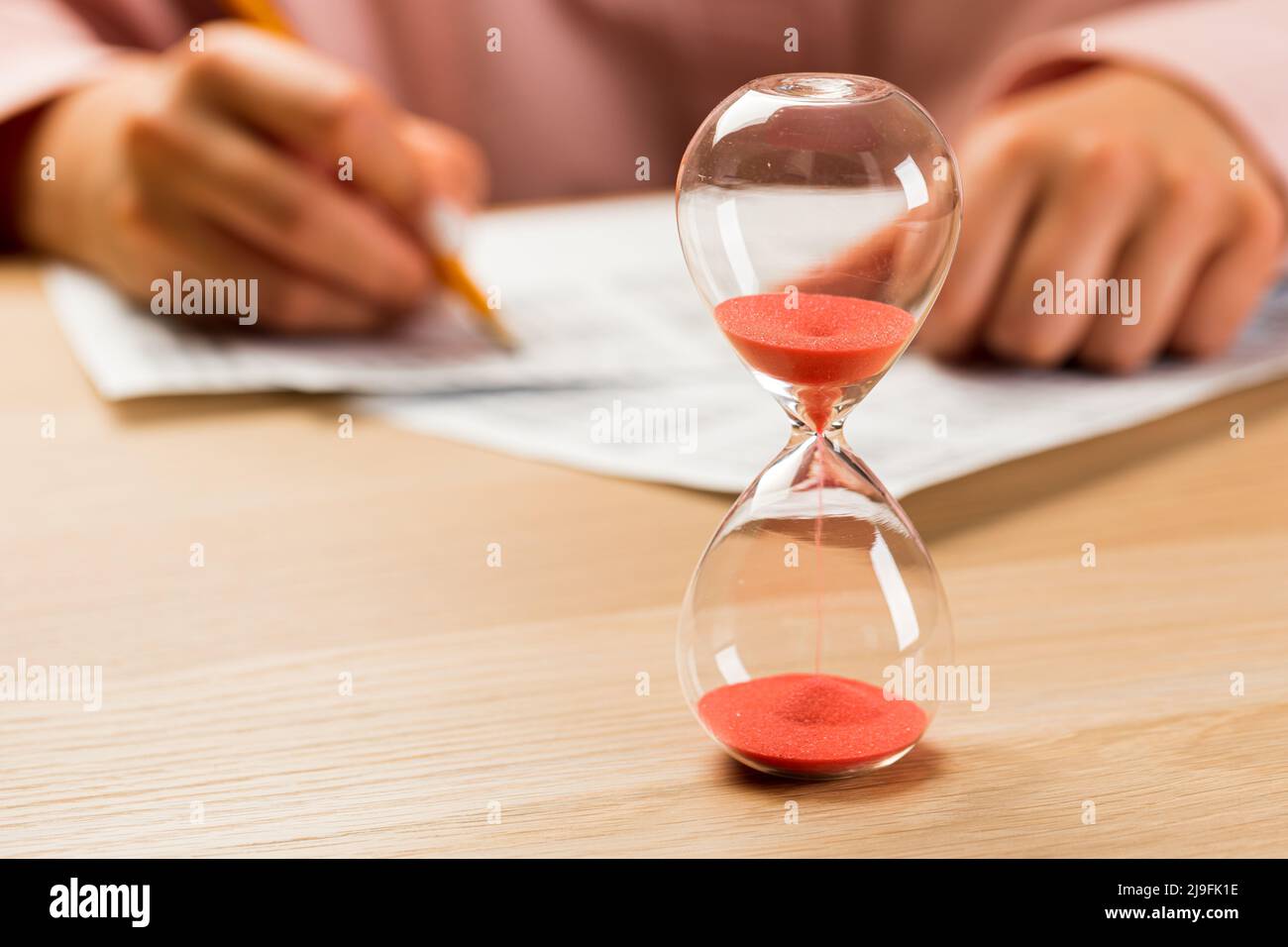 Hourglass with time running out and student hand testing in exercise ...