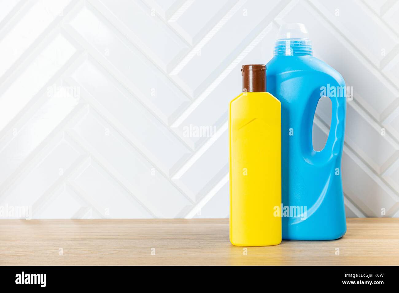 Bottles with detergent and cleaning supplies on wooden table and light ...