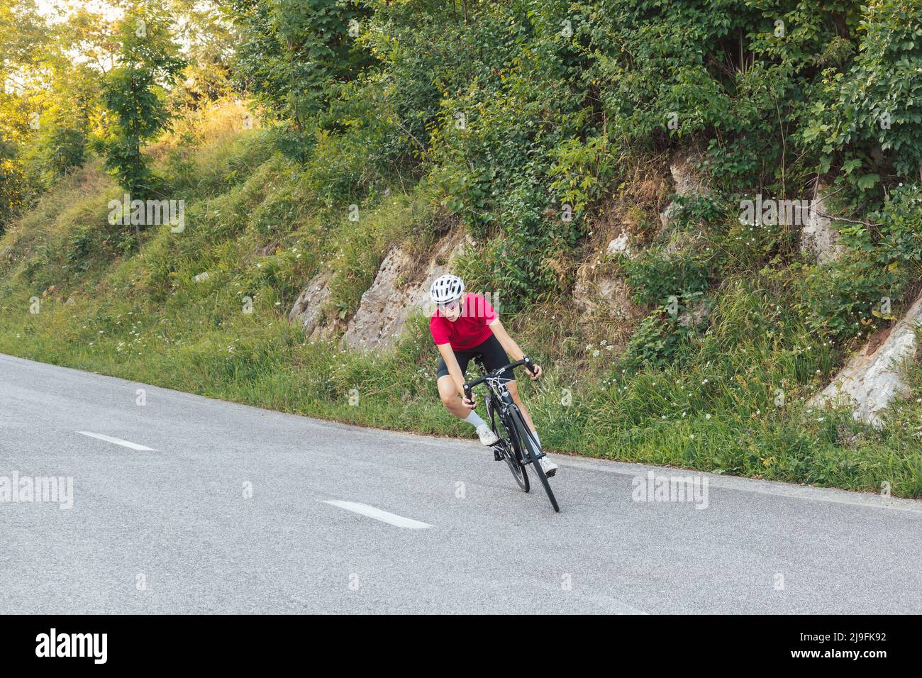 Professional female racing road cyclist riding very fast downhill and ...
