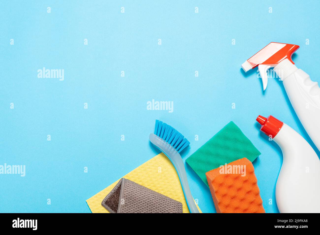 bottles and sprays cleaning agent brushes sponges rags on a colored ...