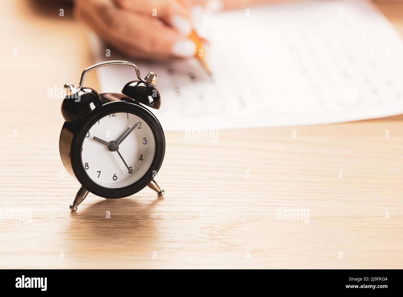 alarm clock with time running out. Students hands to take exams, write ...