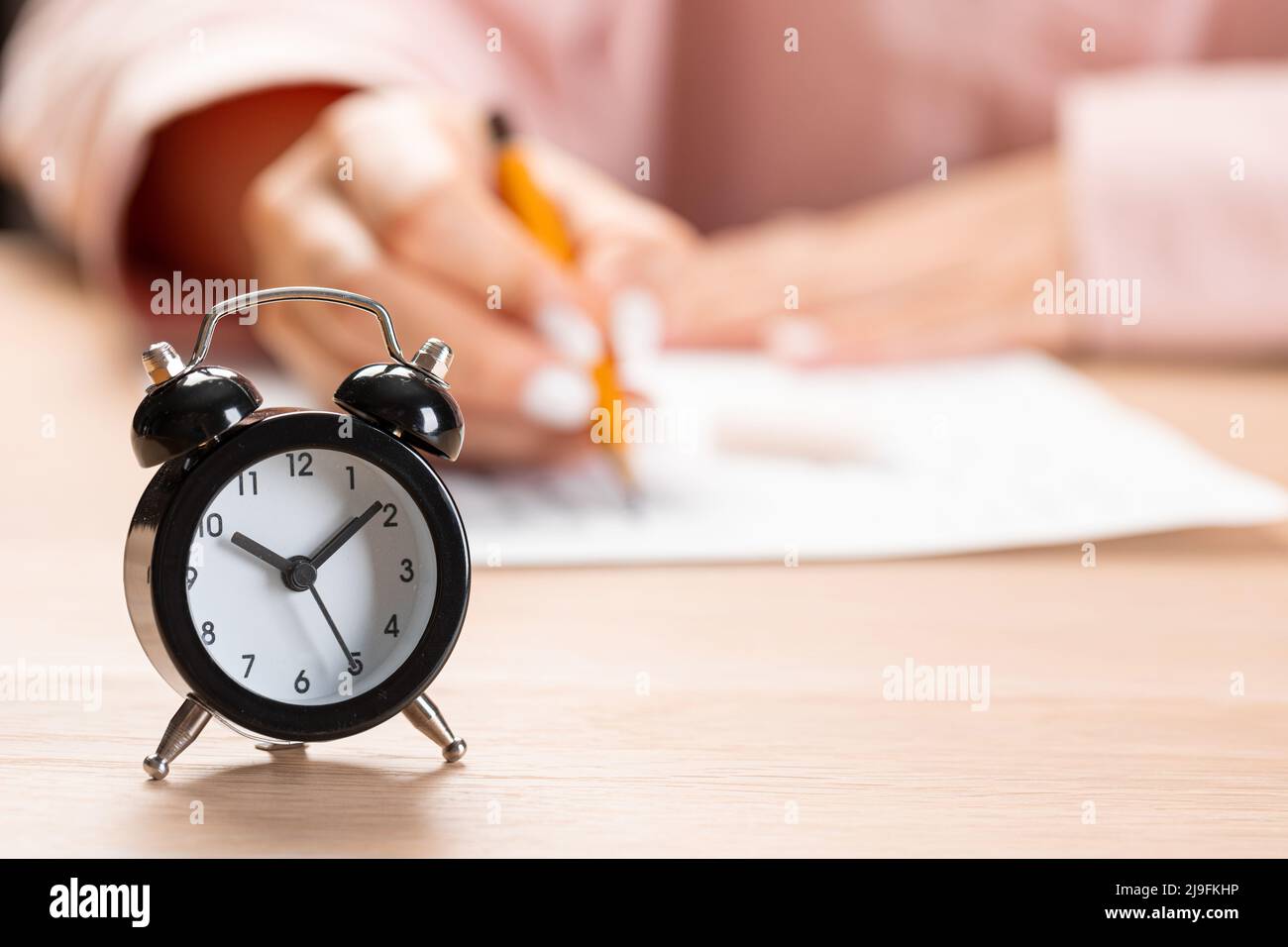 alarm clock with time running out. Students hands to take exams, write ...