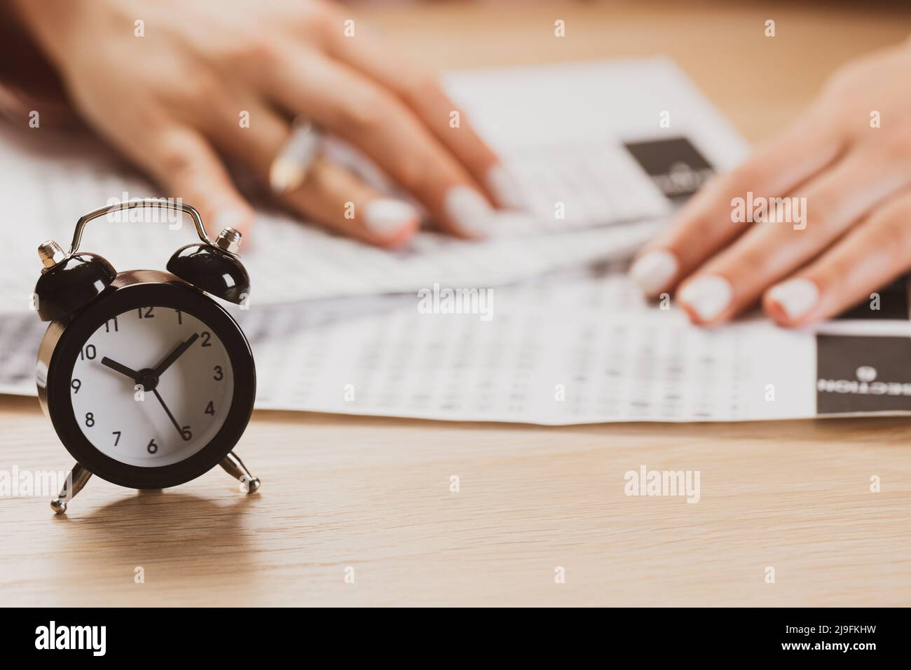 alarm clock with time running out. Students hands to take exams, write ...