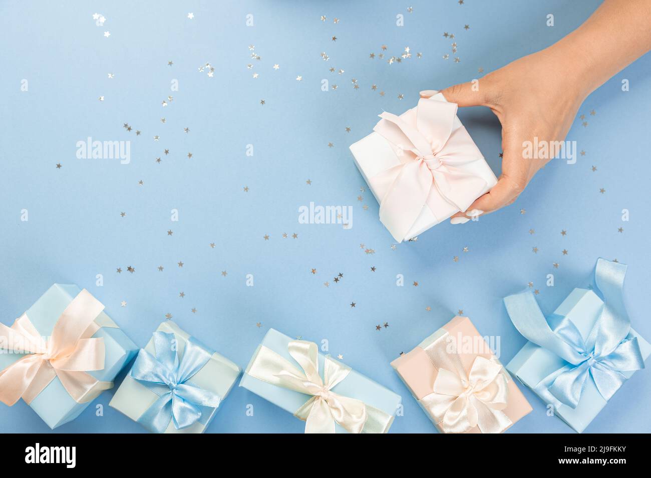 Flat lay of women's hands holding a gift wrapped and decorated with a ...