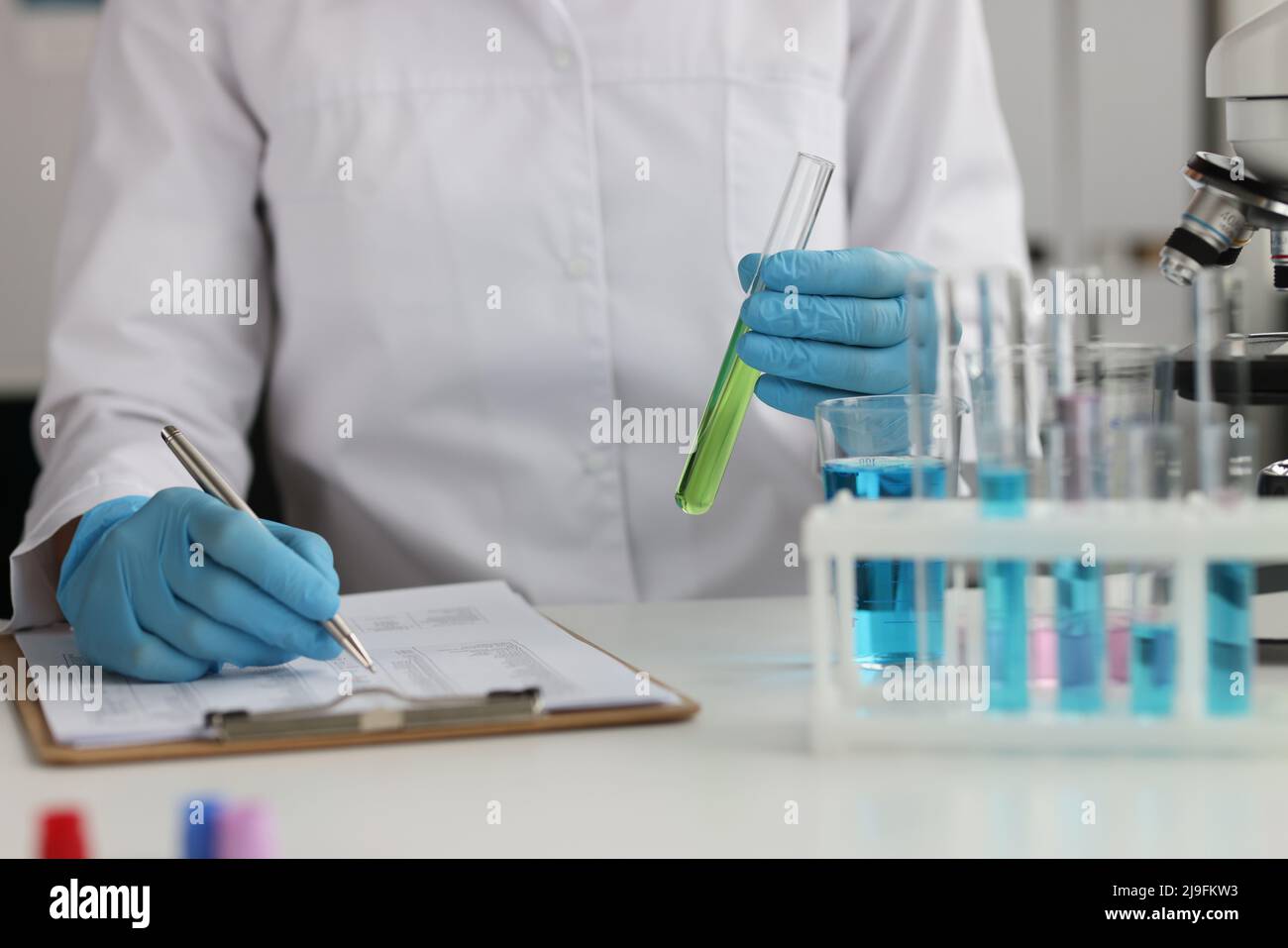 Researcher holds test tube with green liquid records data Stock Photo ...