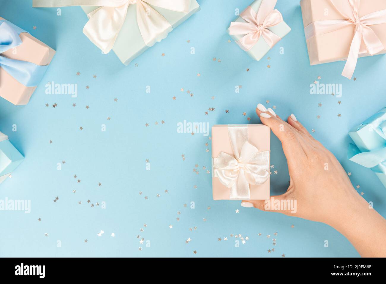 Flat lay of women's hands holding a gift wrapped and decorated with a ...