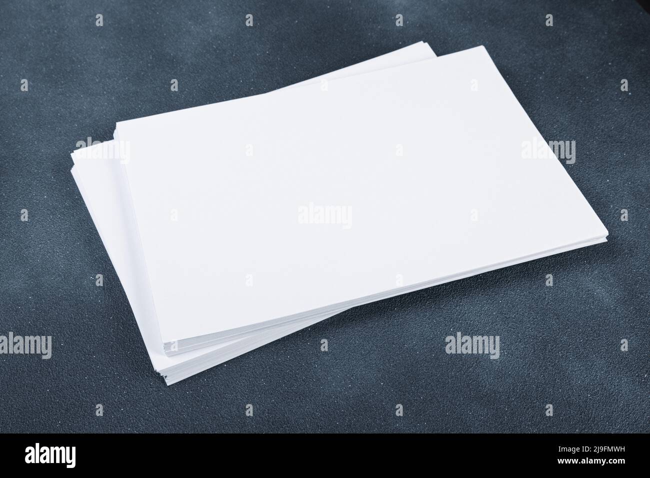 White business card sheet of paper a4 stack on a dark table. cold toned ...