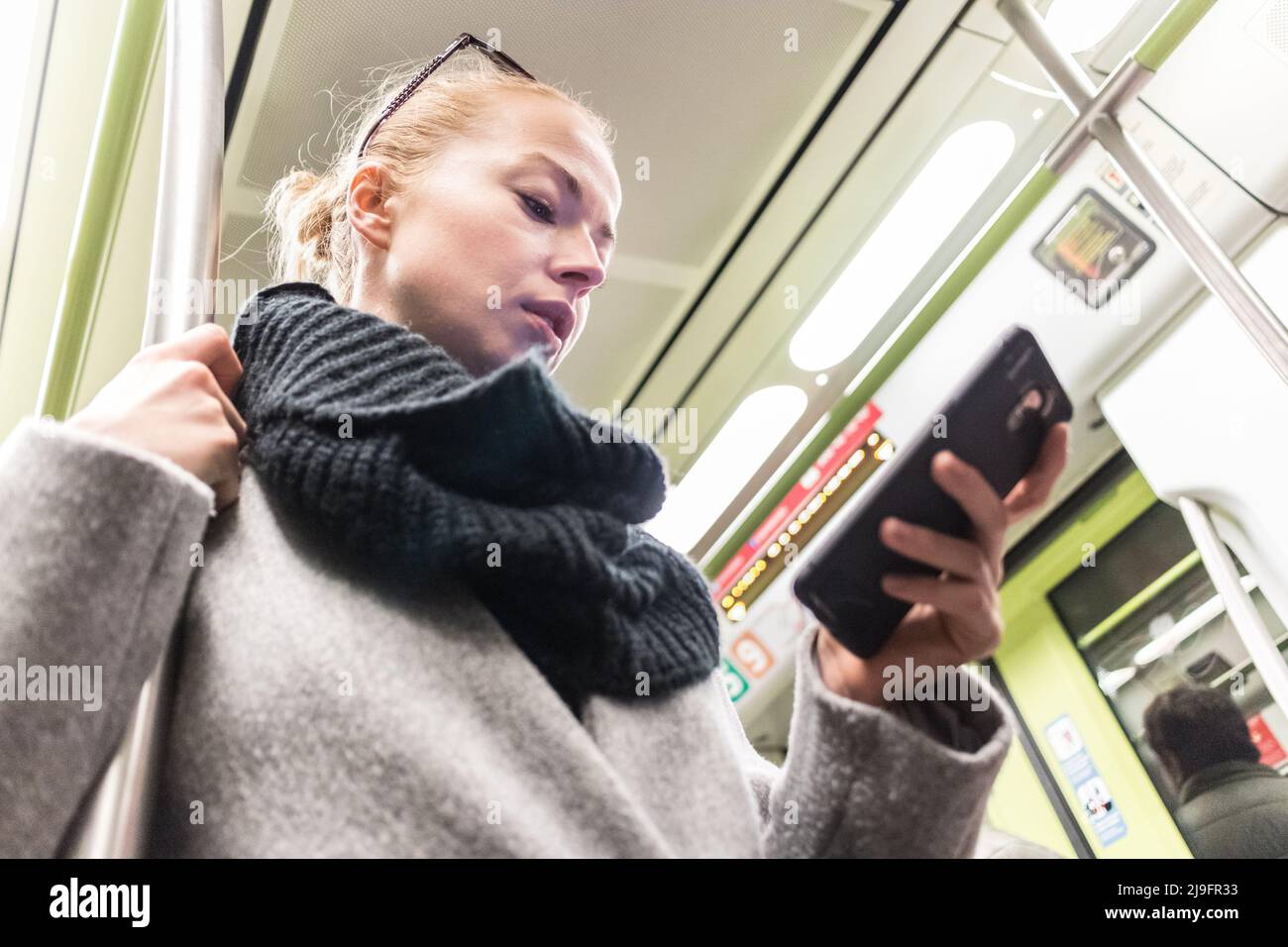 Young woman passenger using smartphone while moving in the modern metro ...