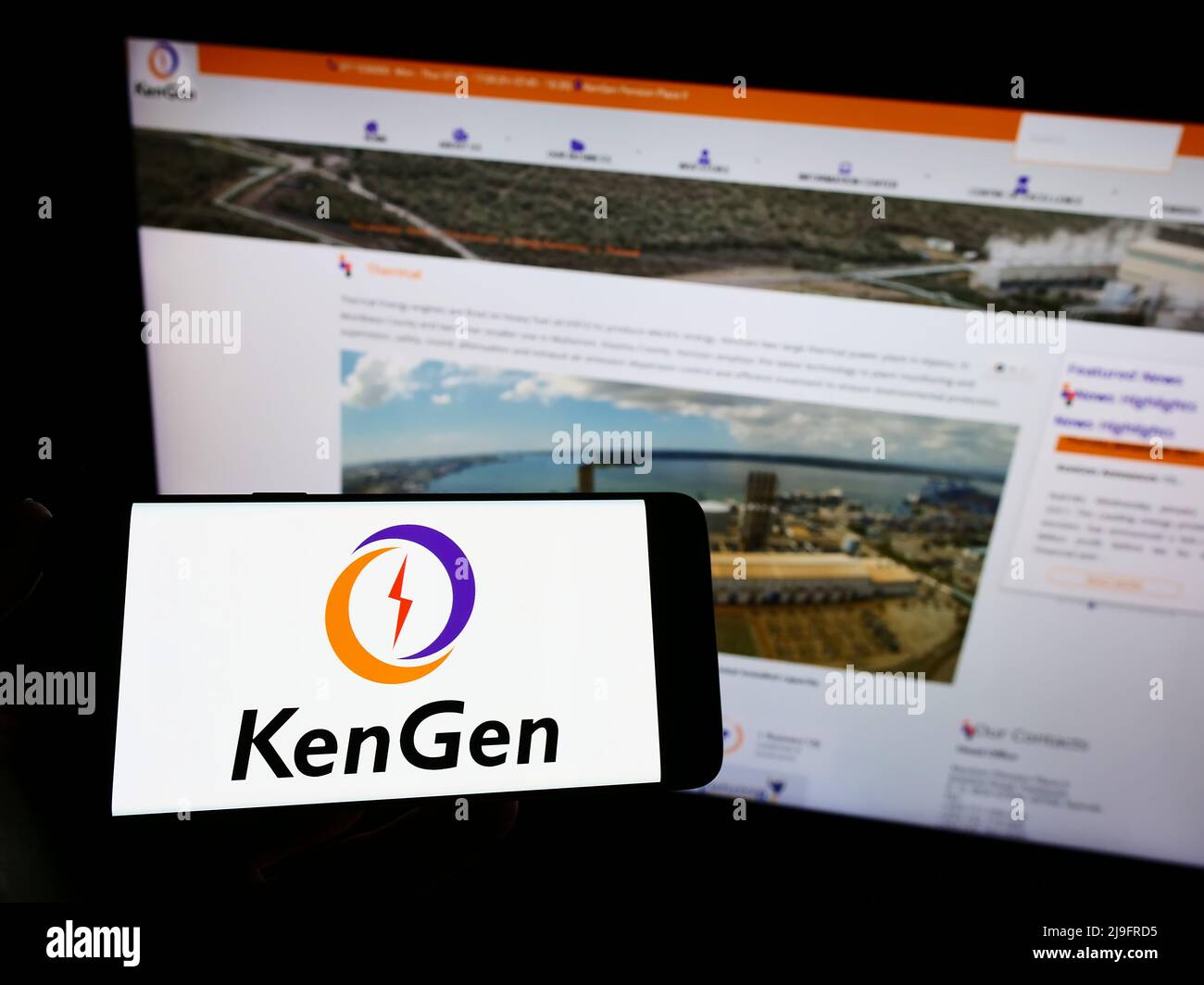 Person holding smartphone with logo of Kenya Electricity Generating ...