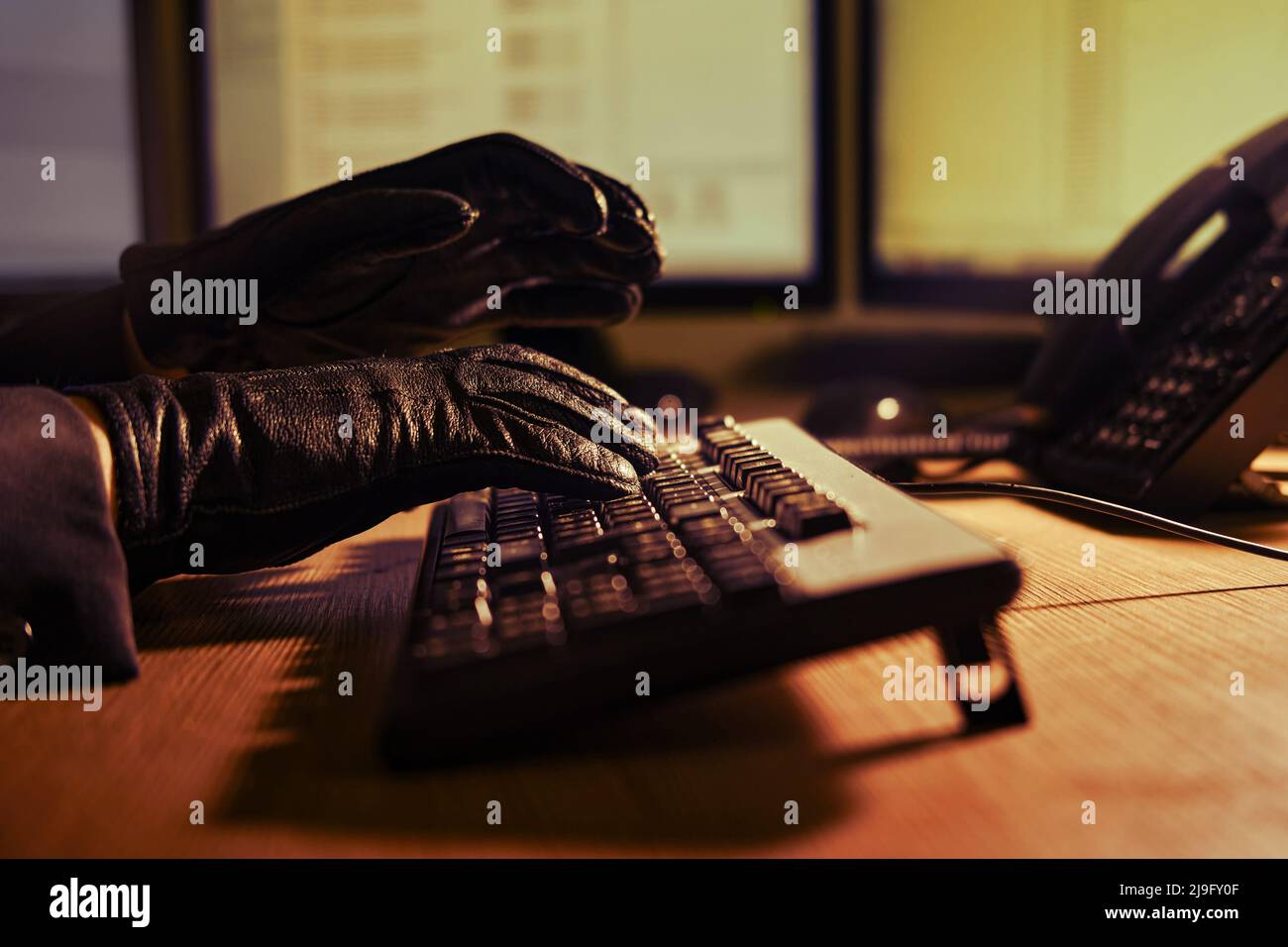 Man attacker hacker in black gloves on his hands working on a computer ...