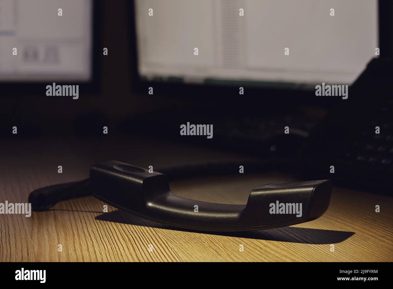 Handset of the landline phone lies on the office desk with computer ...