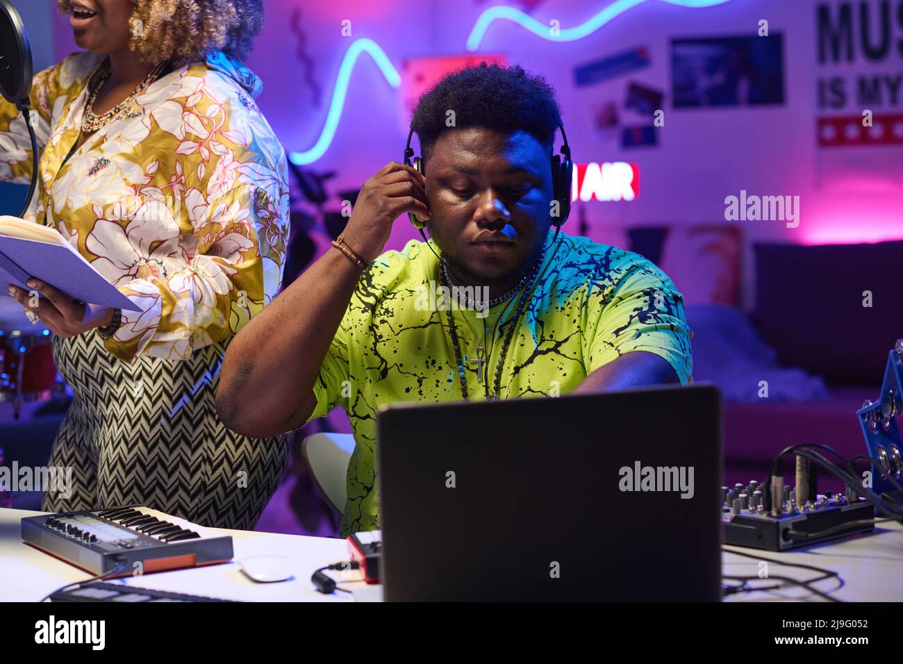 Modern young African American man wearing headphones working with ...