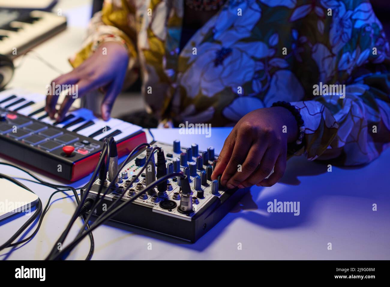 Unrecognizable young Black female musician sitting at desk working on ...