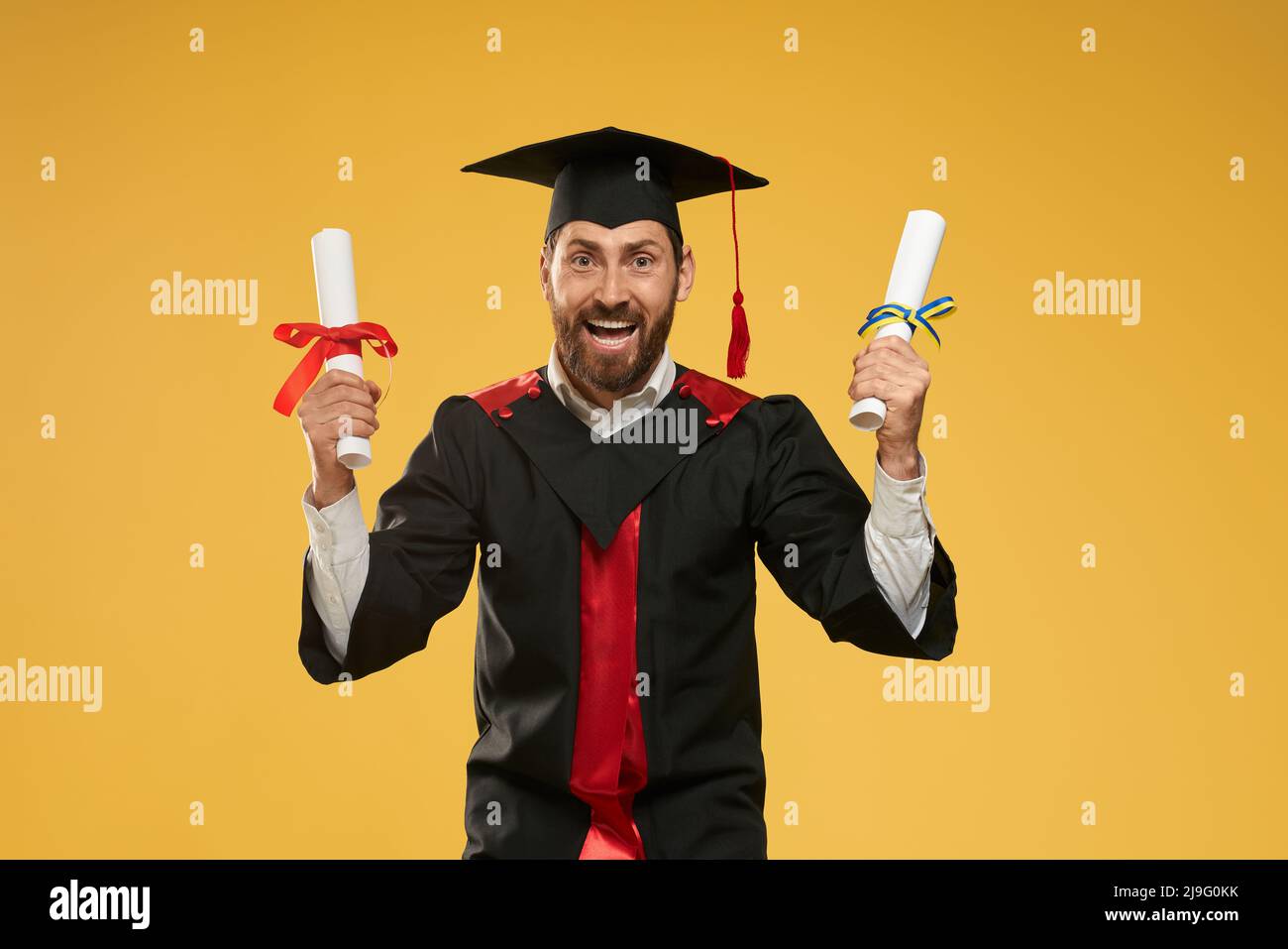 Front view of man wearing mortarboard and graduate gown standing with ...