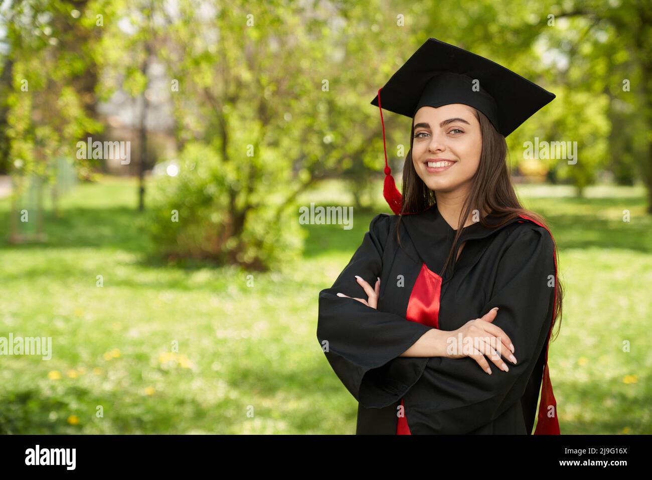Front view of girl wearing mortarboard and graduate gown smiling ...