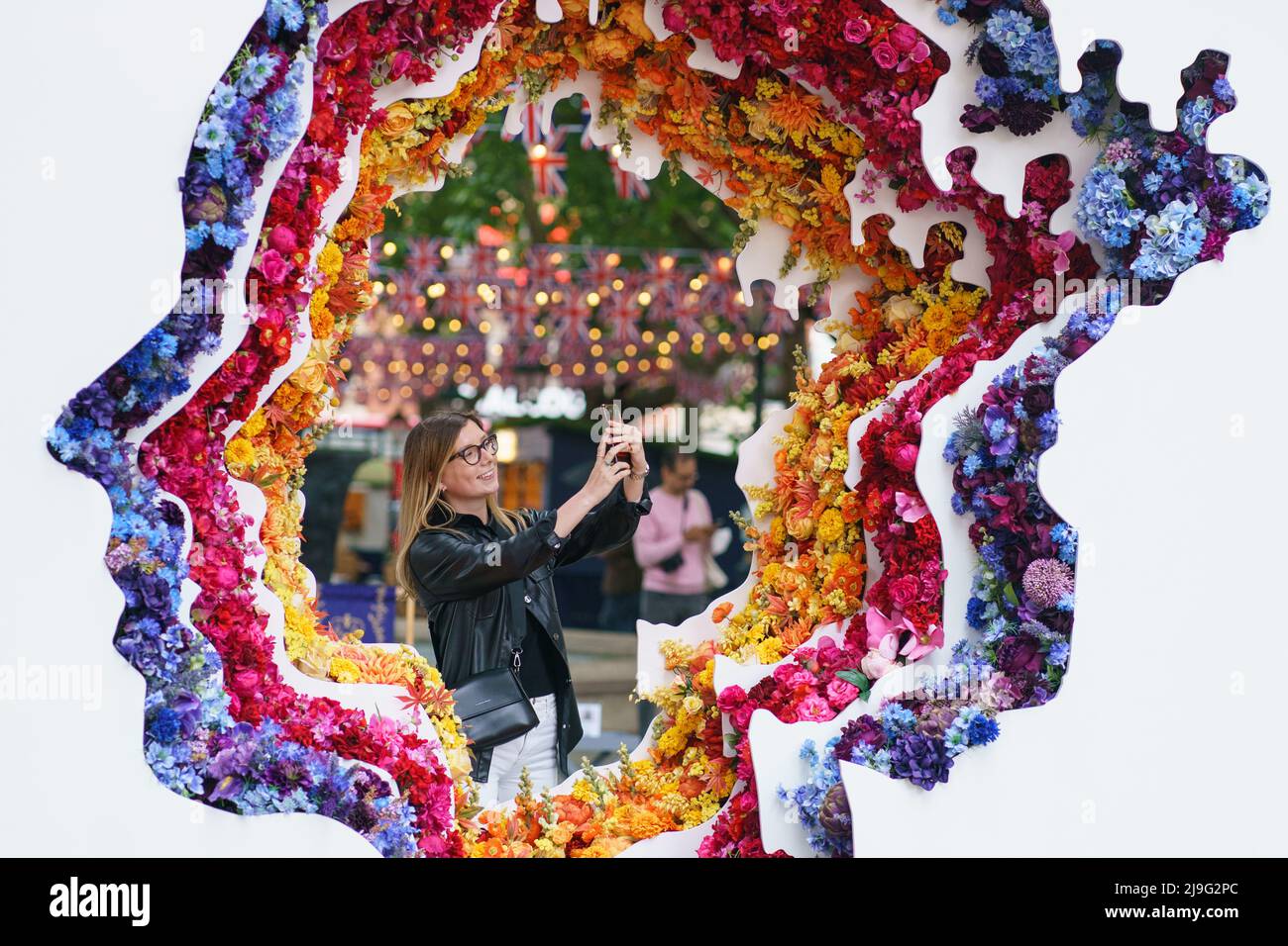 A woman takes a photo of a Queen's Head floral installation by Veevers ...