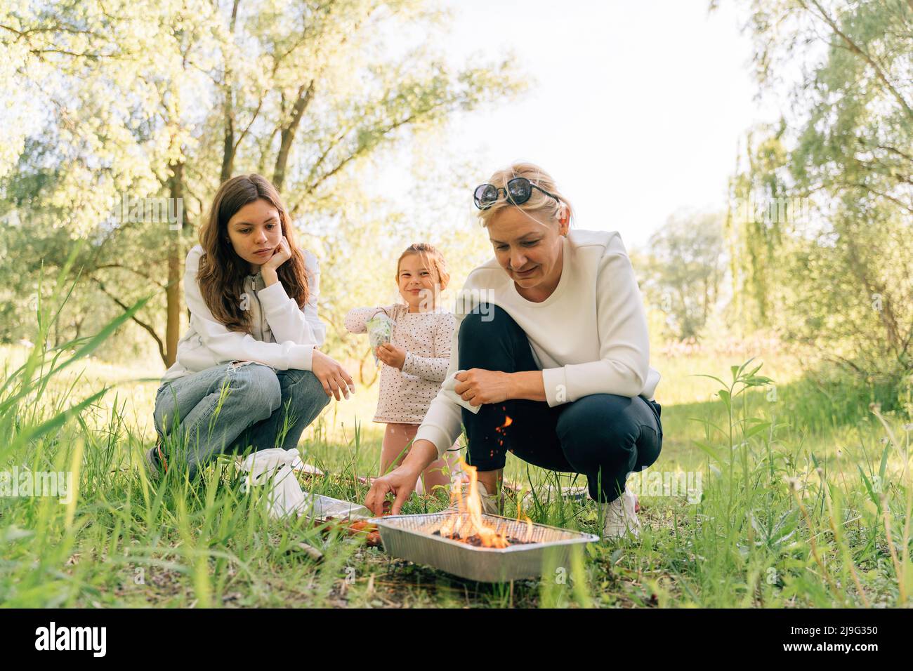 Family with small child, teen and grandmother doing bbq on the nature ...