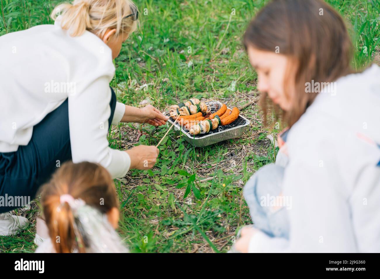 Family with small child, teen and grandmother doing bbq on the nature ...