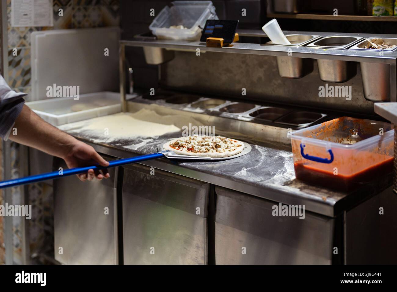 Getting ready to place tasty Italian pizza in the oven. Chef in the ...