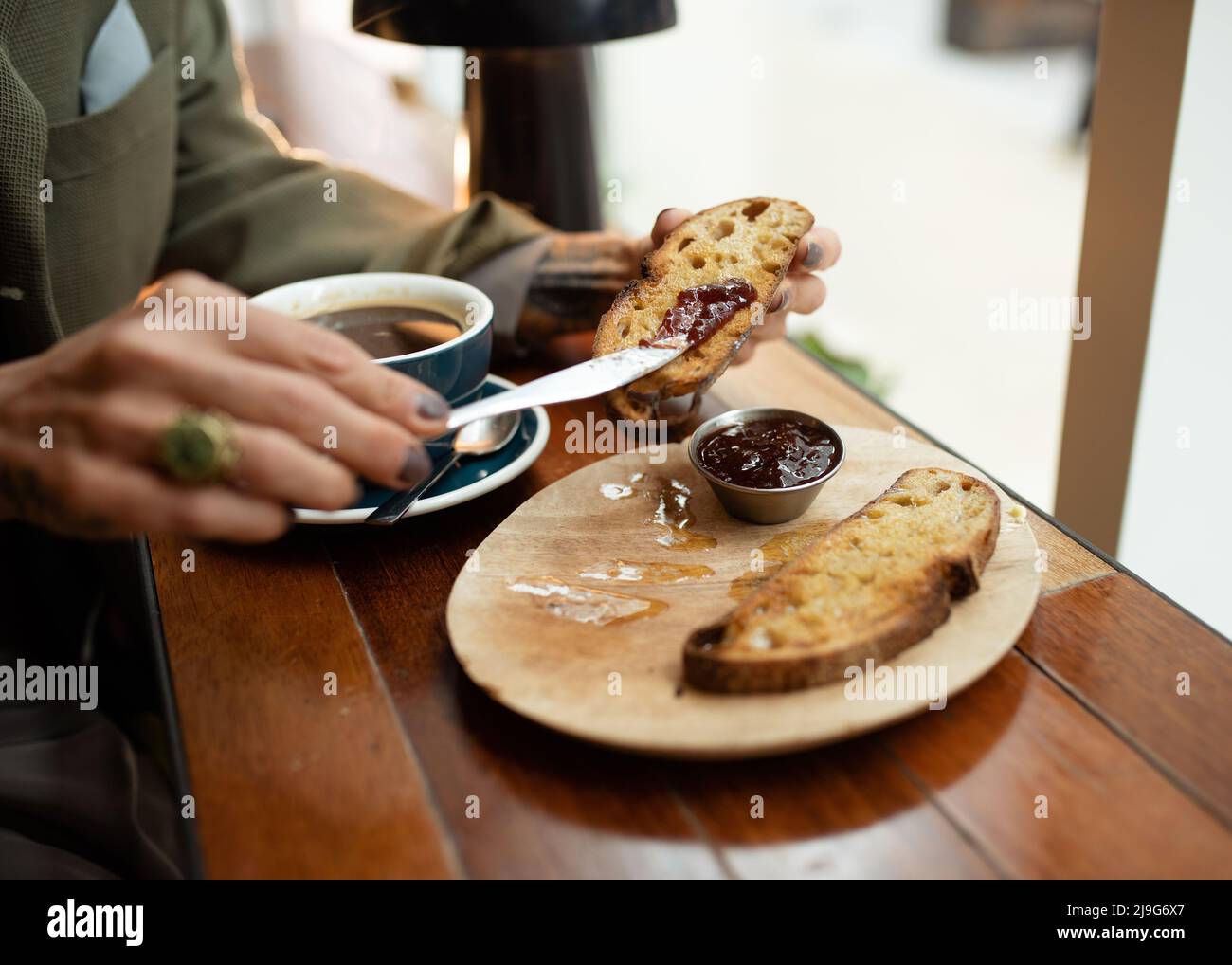 person eating breakfast toast and jam and drinking coffee in the cafe ...