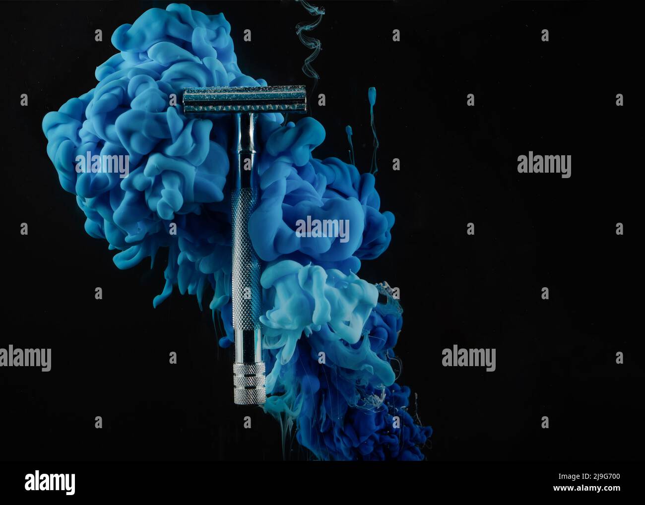 safety razor in water surrounded with dramatic blue colorful cloud of ...