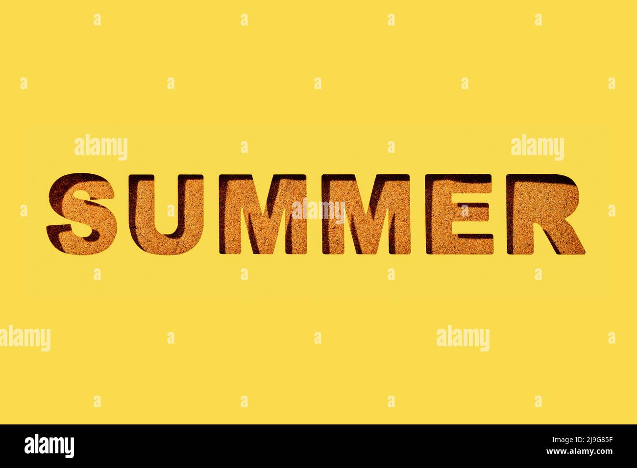 the word summer cut out on a yellow paper, and some sand in the ...