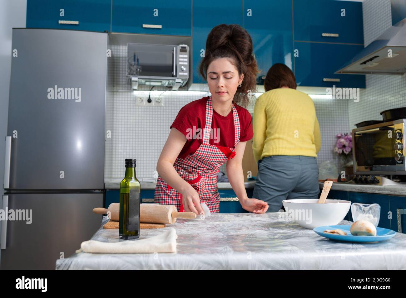 Two beautiful young women prepare food together in the kitchen ...