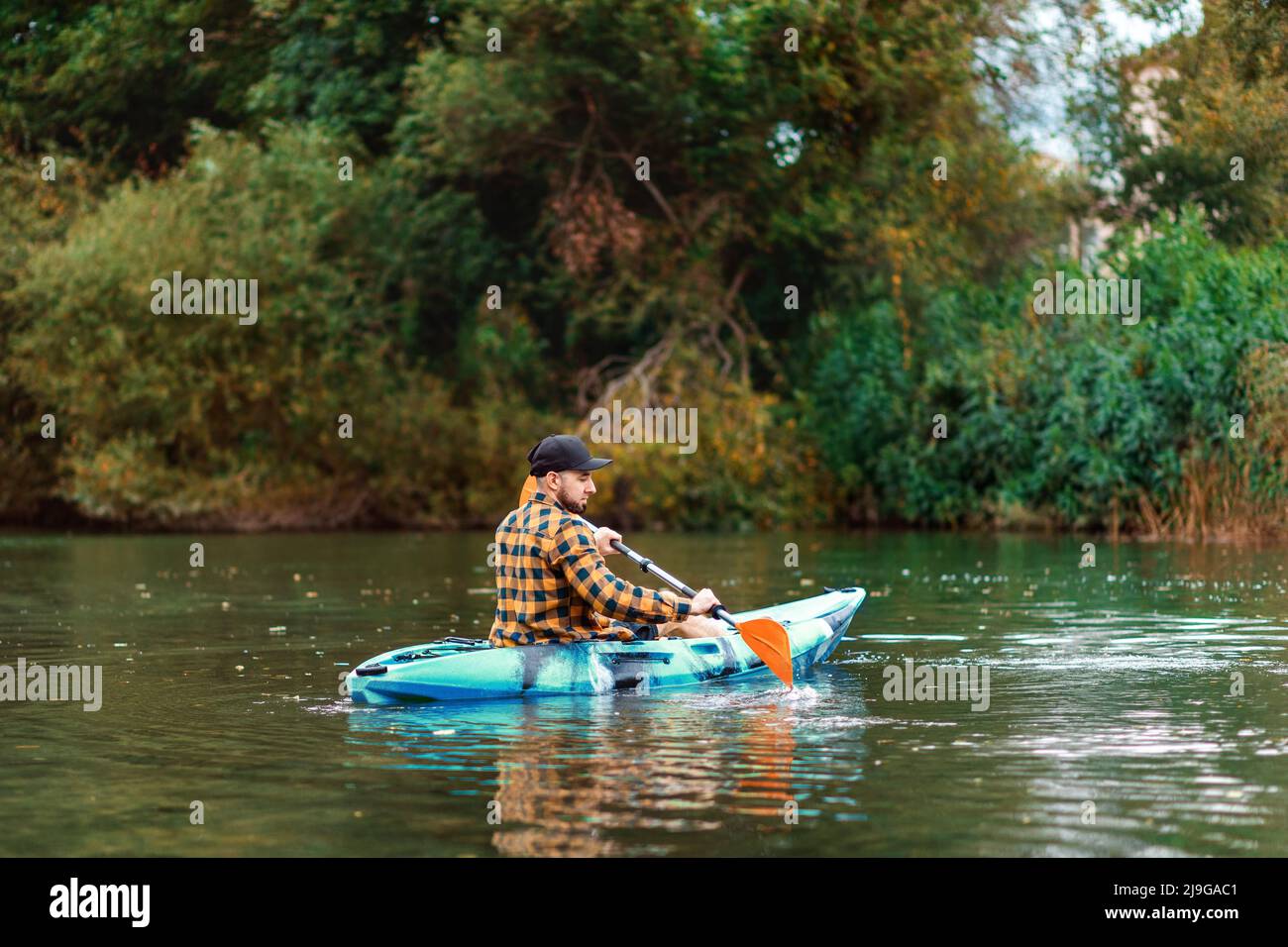 Watersport. Adult caucasian bearded man kayaking at the river. Back ...