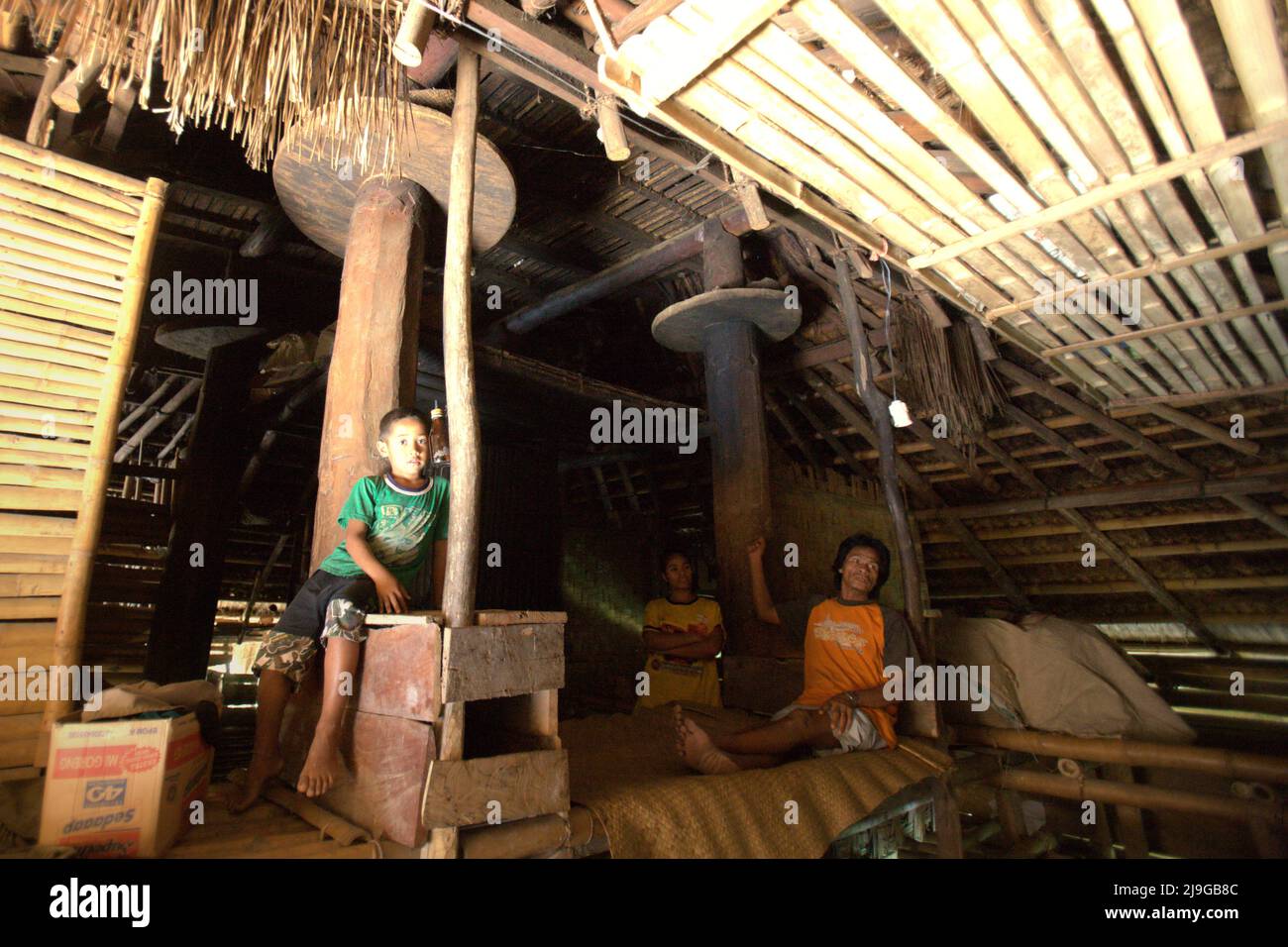 Umbu Tiu, a villager, with his wife and child inside their traditional ...