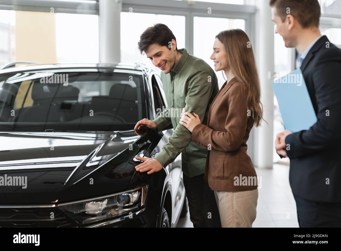 Millennial Caucasian couple choosing new car, communicating with auto ...