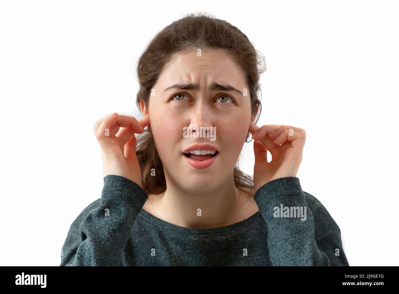 A young woman covers her ears from the noise. Emotion of discontent and ...