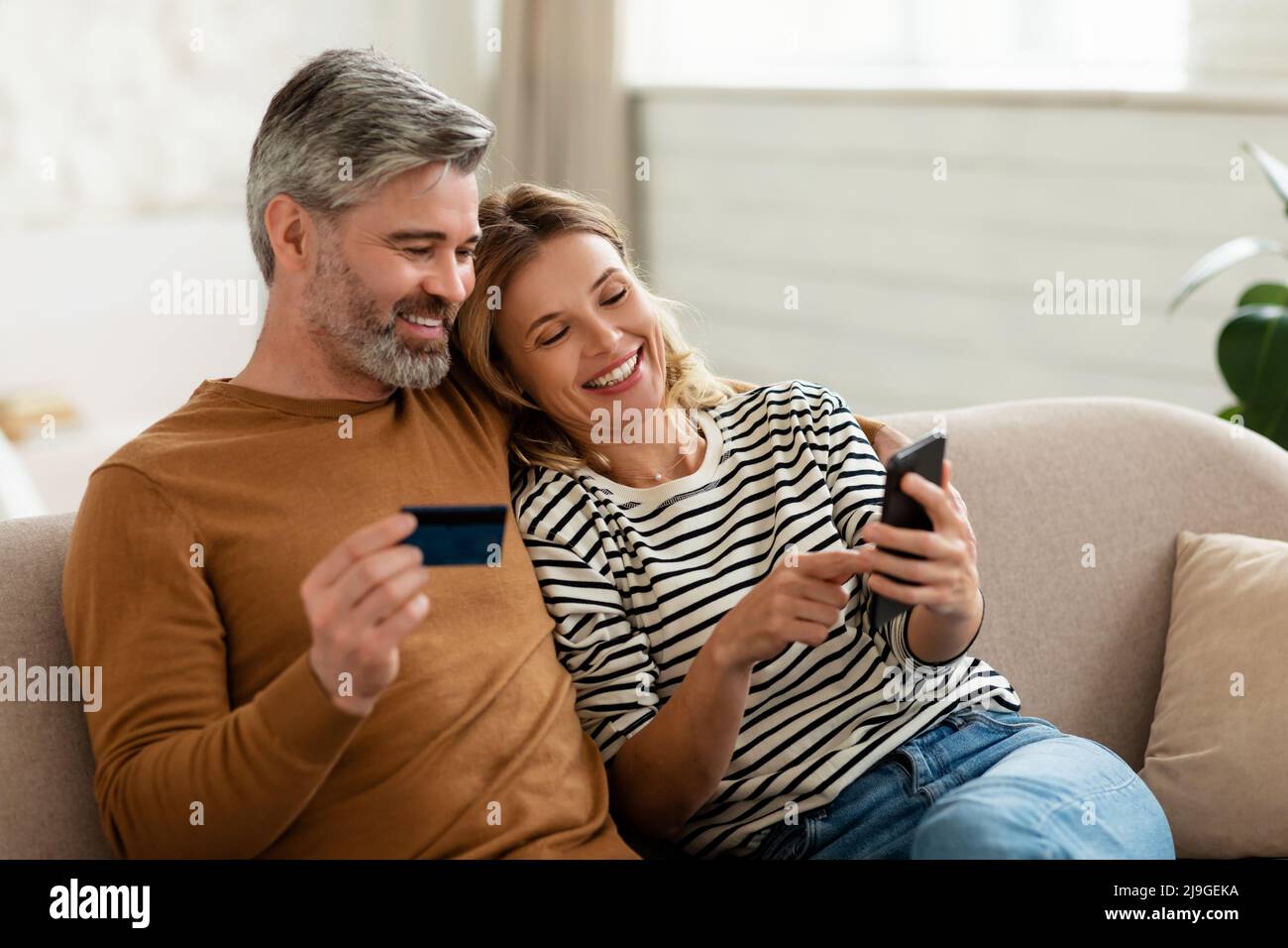Husband And Wife Shopping Using Phone And Credit Card Indoor Stock ...