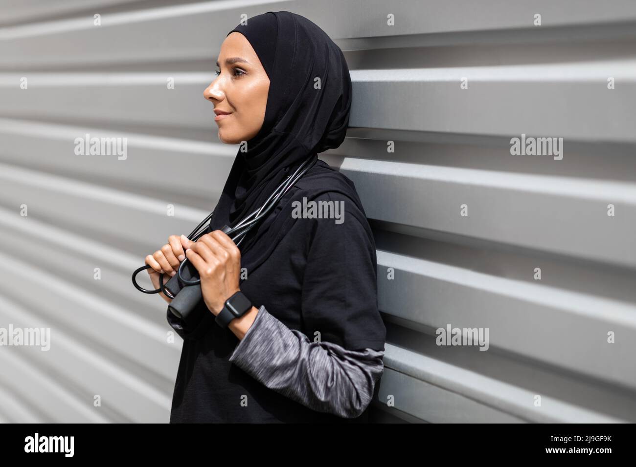 Happy calm young middle eastern lady in hijab with skipping rope ...