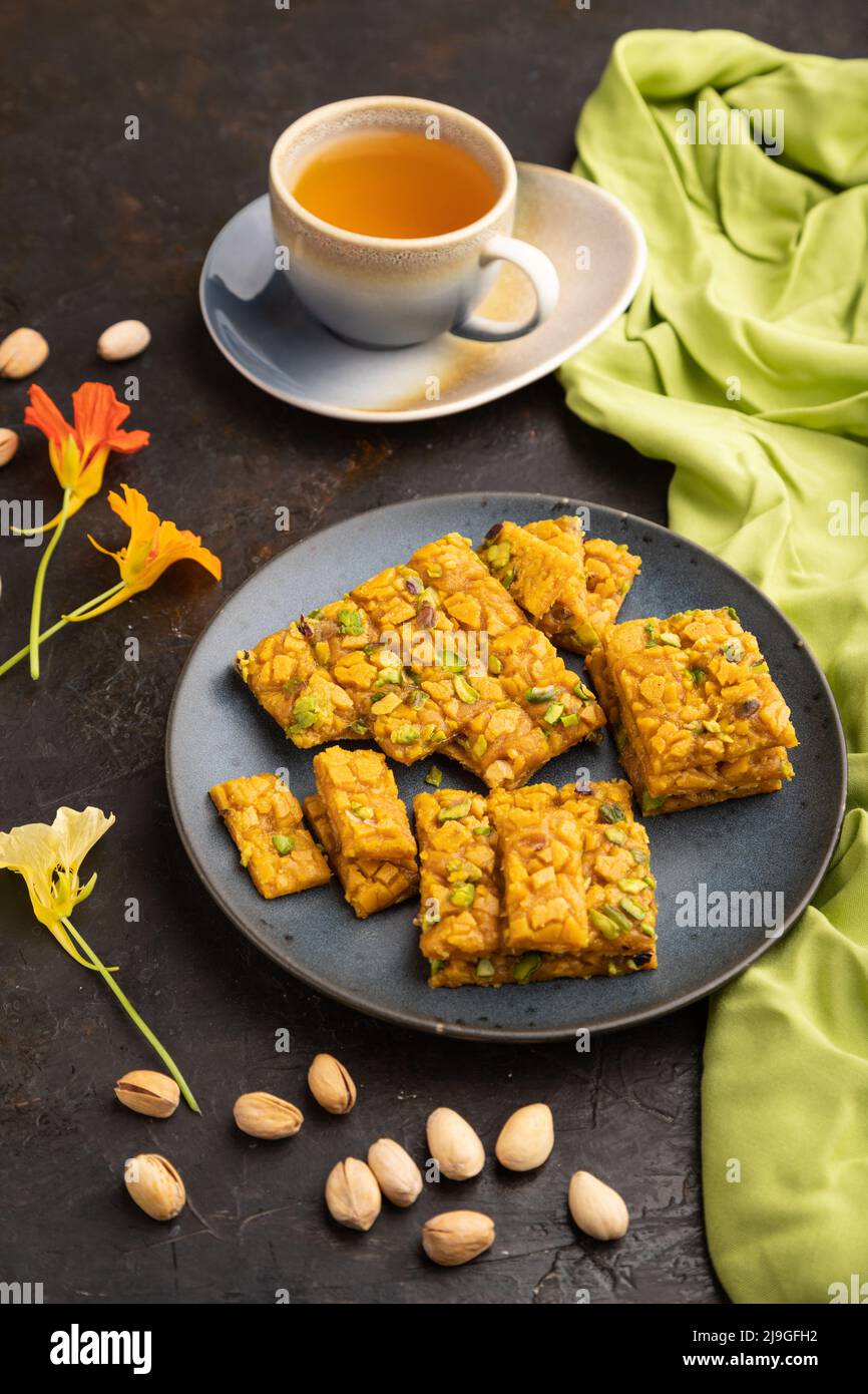 Traditional iranian dessert sohan with cup of green tea on a black ...