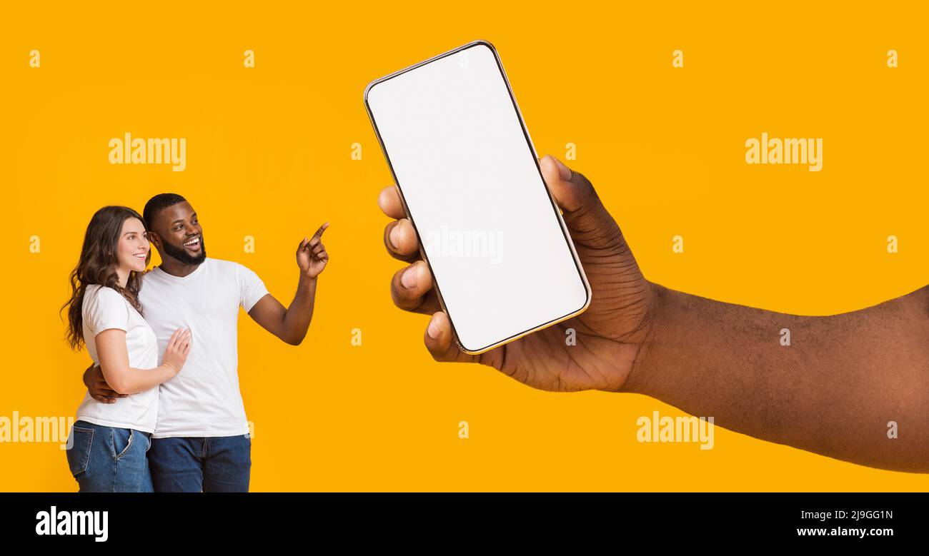 Interracial couple showing blank empty smartphone screen for mockup ...