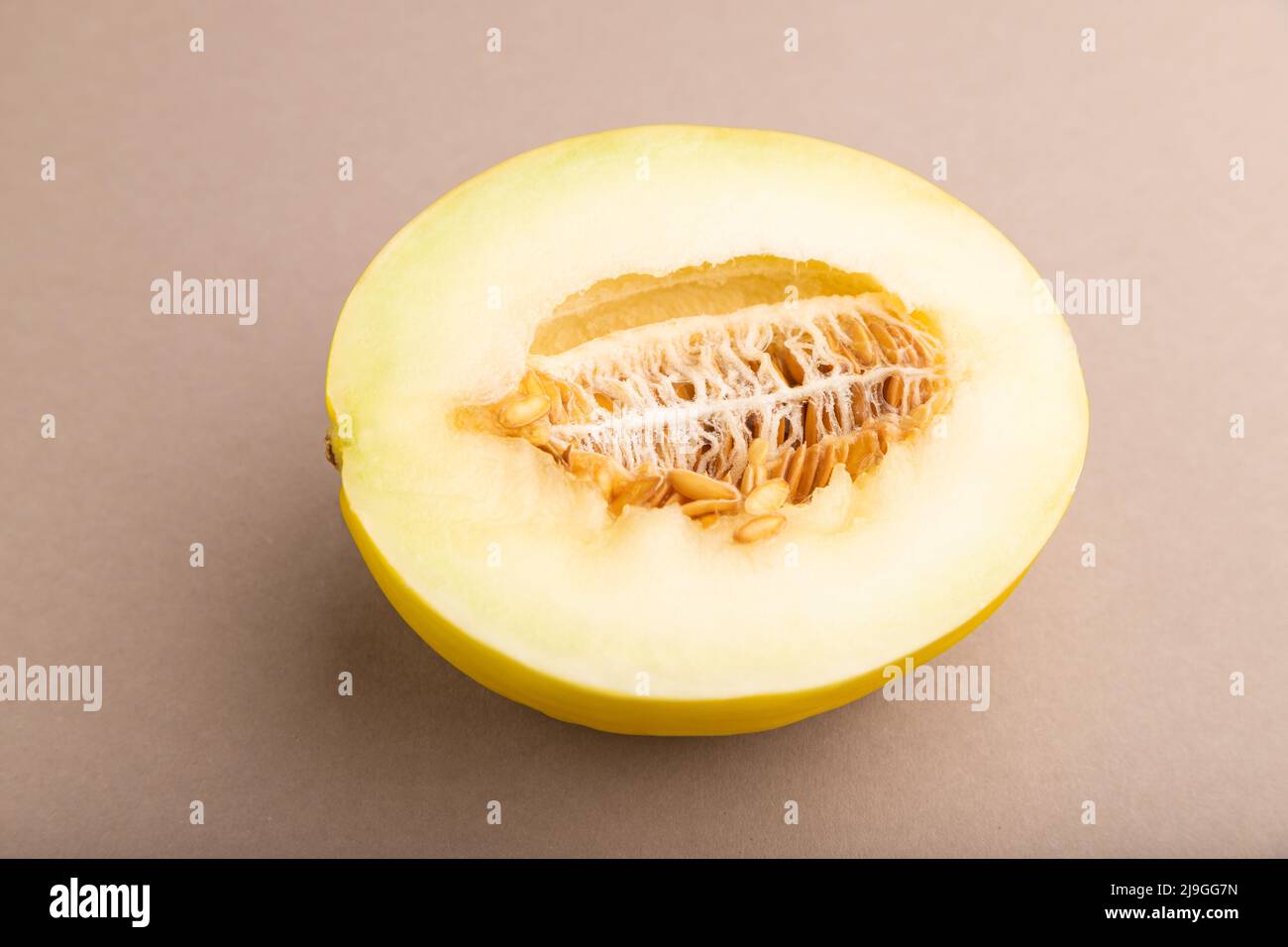 Sliced ripe yellow melon on brown pastel background. Side view, close ...
