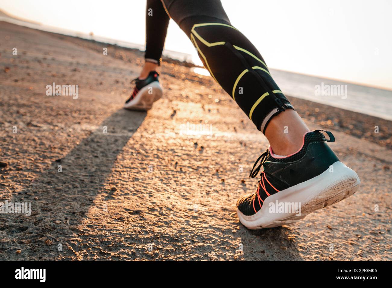Sports and running. A woman runs along the sea. Close-up of feet in ...