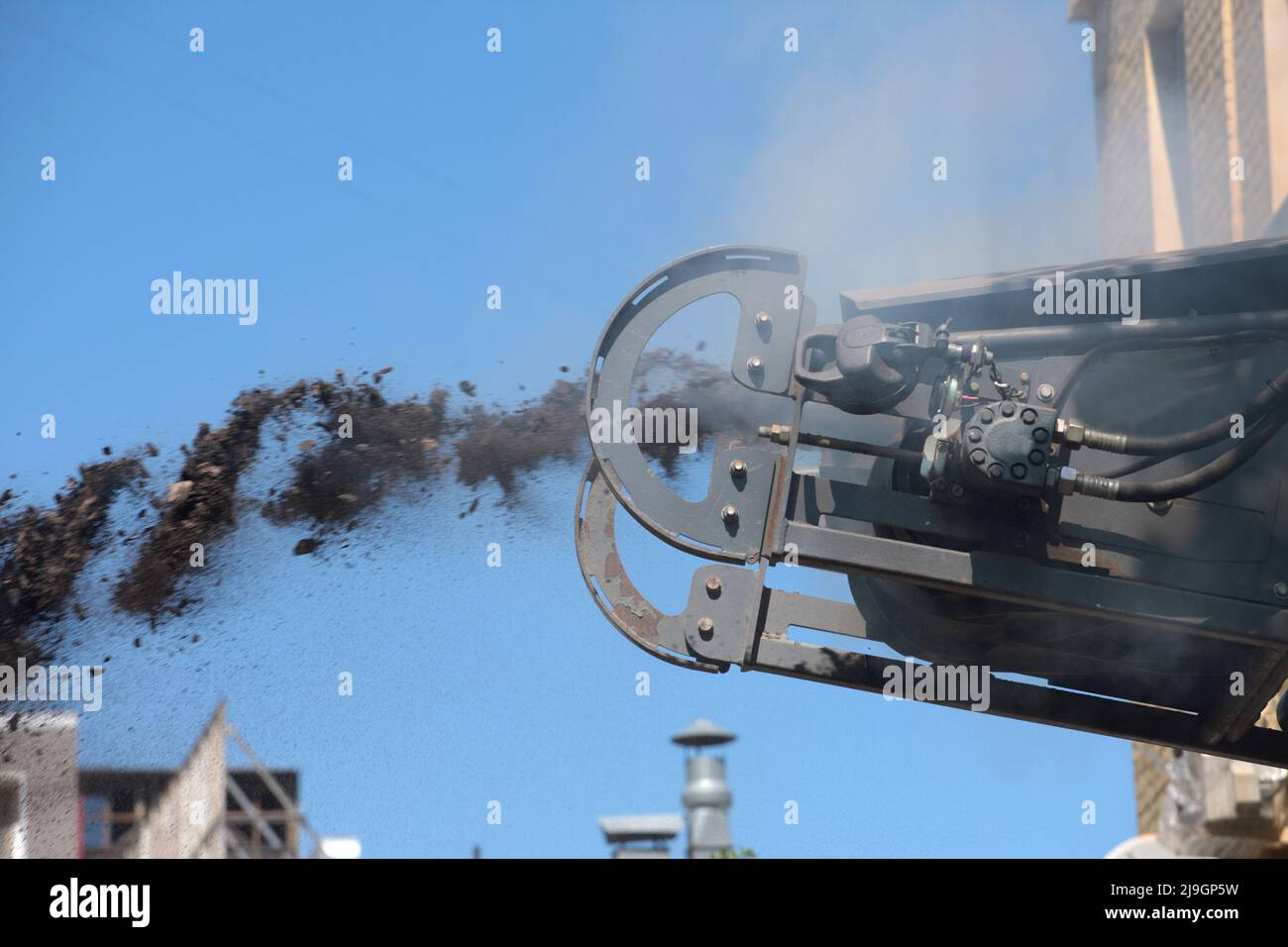 Road milling vehicle loads milled asphalt into dump truck inside a ...