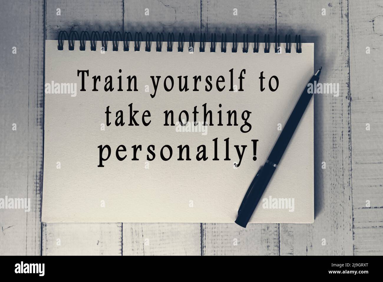 Motivational quote on notepad with pen on wooden desk - Train yourself ...