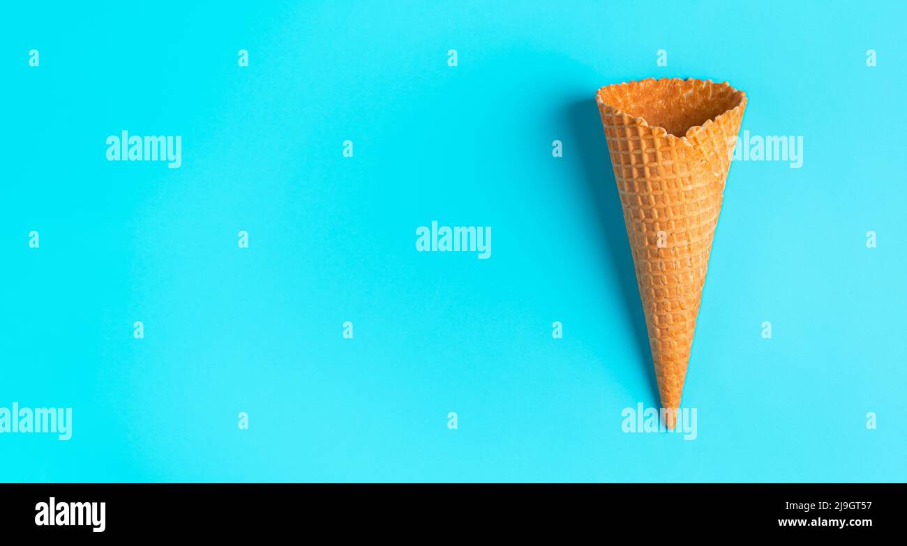 An empty ice cream cone on a blue background Stock Photo - Alamy