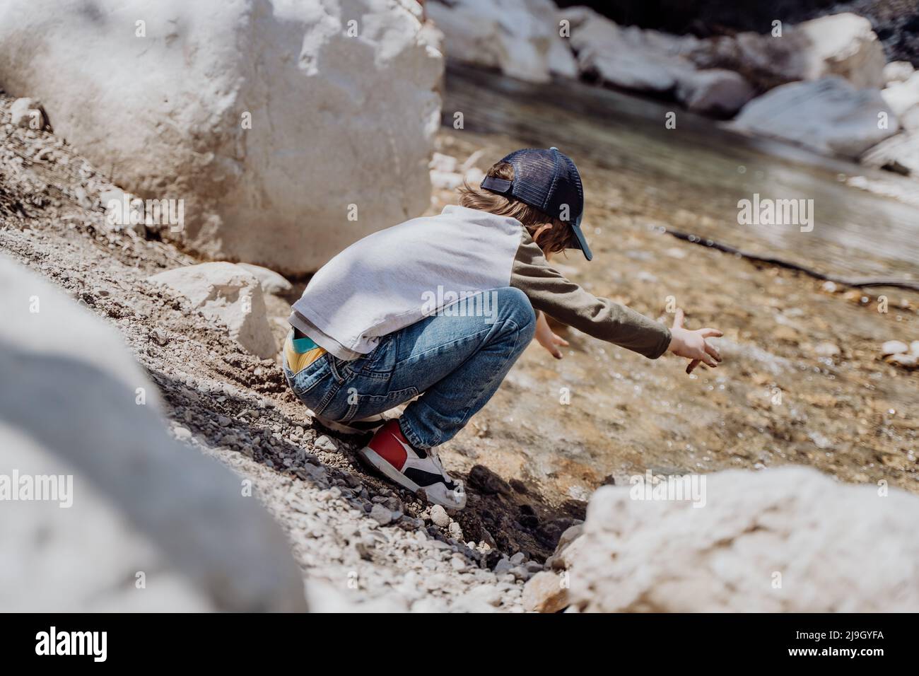 Caucasian school boy throwing rocks into the canyon river. Kid child ...