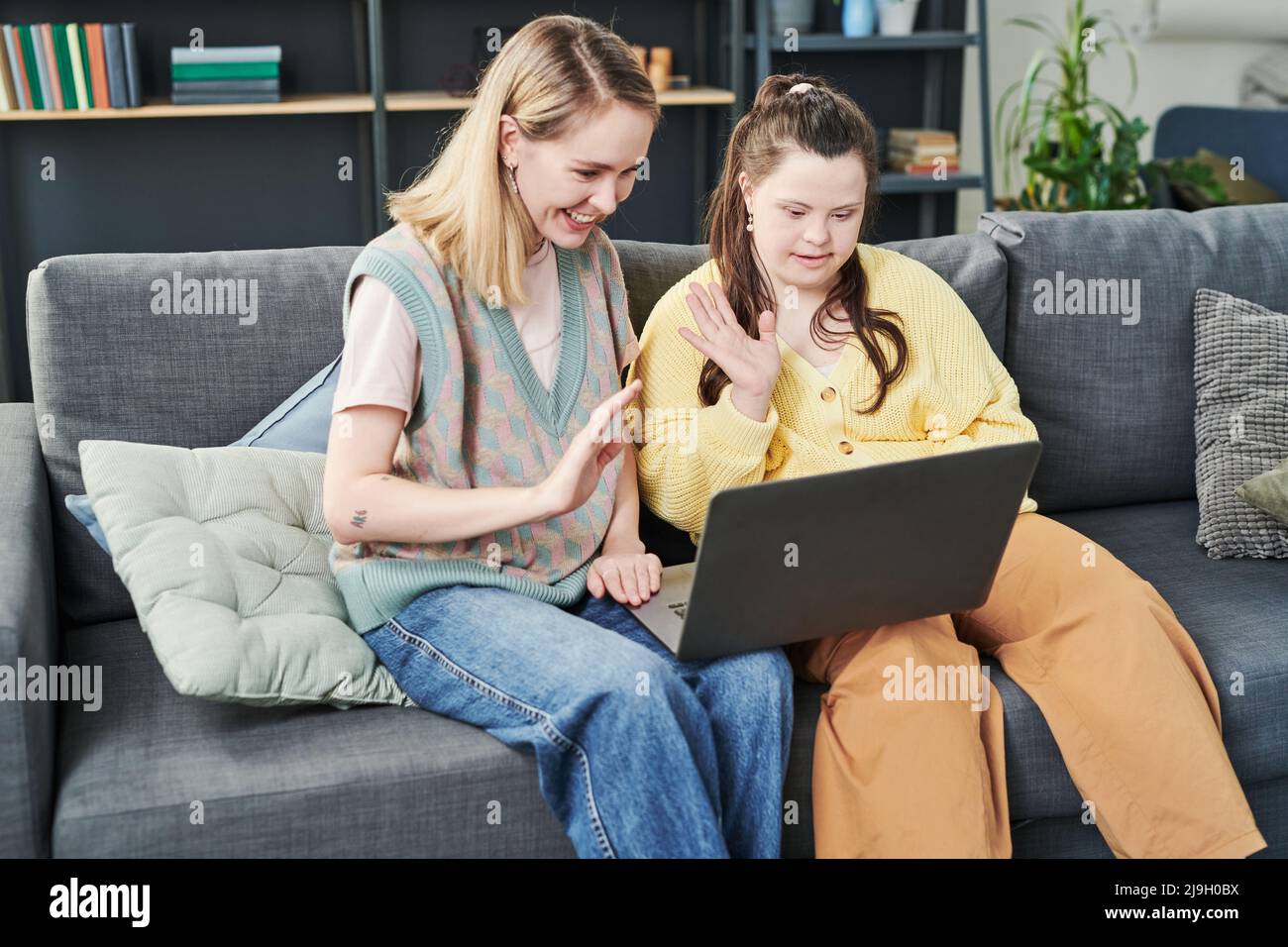 Young Caucasian woman and her sister with Down syndrome sitting on ...