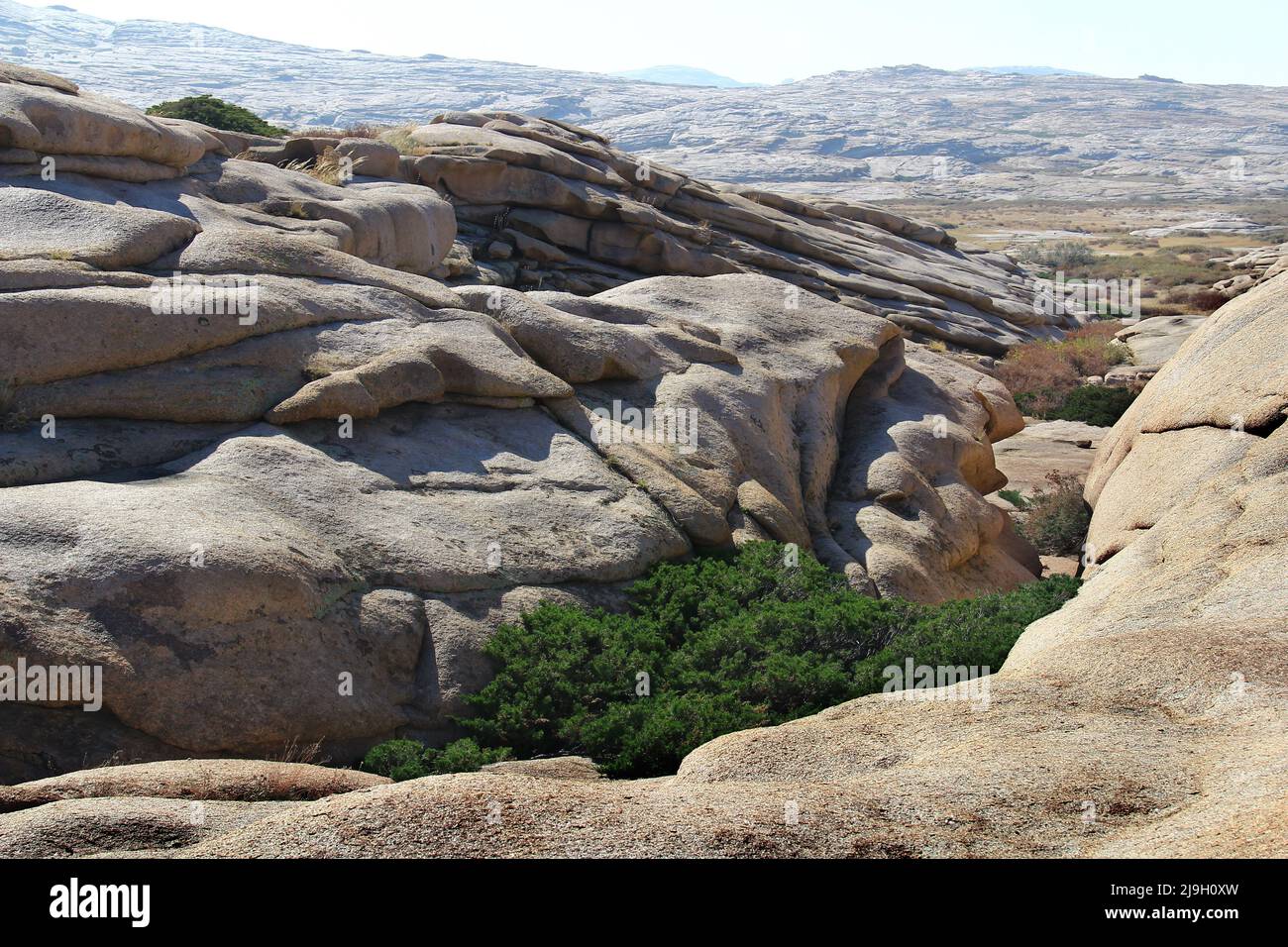 Stone undulating slopes of volcanic mountains with green bushes in the ...