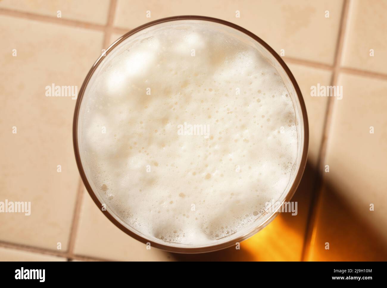 Glass of fresh lager beer with White fresh Foam on table. Beer foam top ...