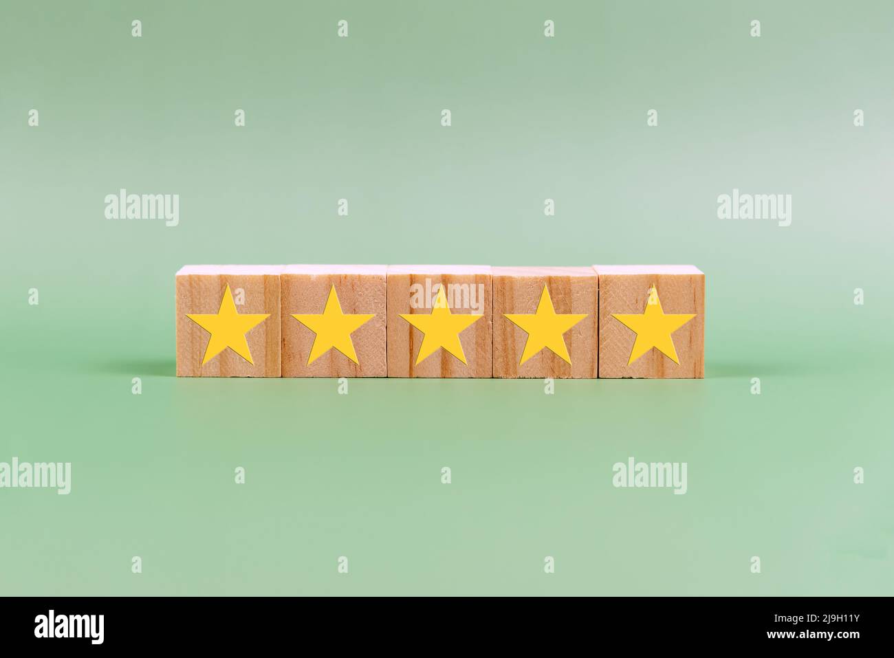 5 star rating on wood block on green background Stock Photo - Alamy