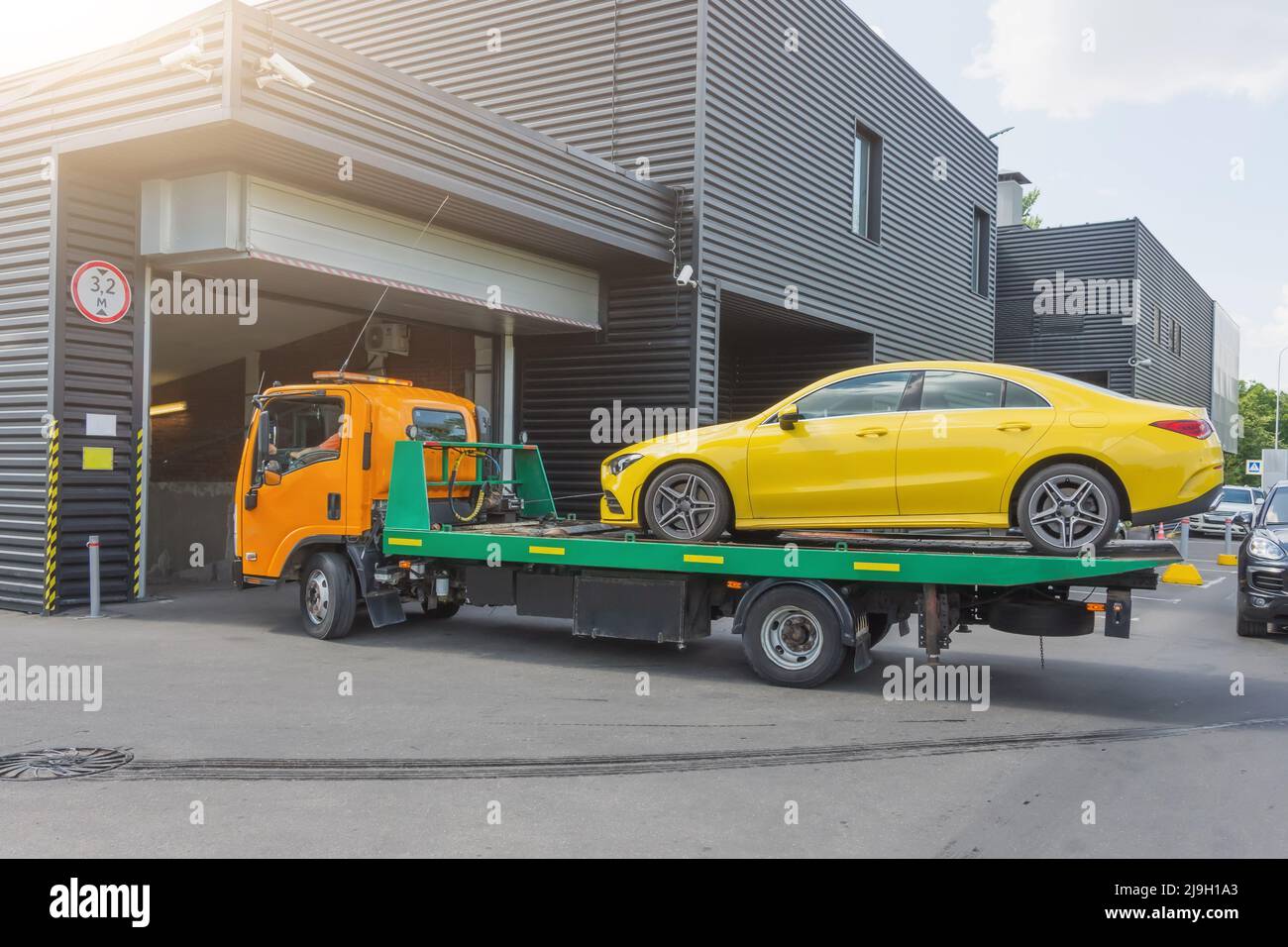 Tow truck drives into an underground garage with a loaded yellow car ...