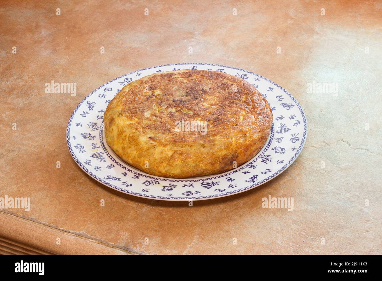 A large homemade potato omelet on a decorative plate on a rustic ...