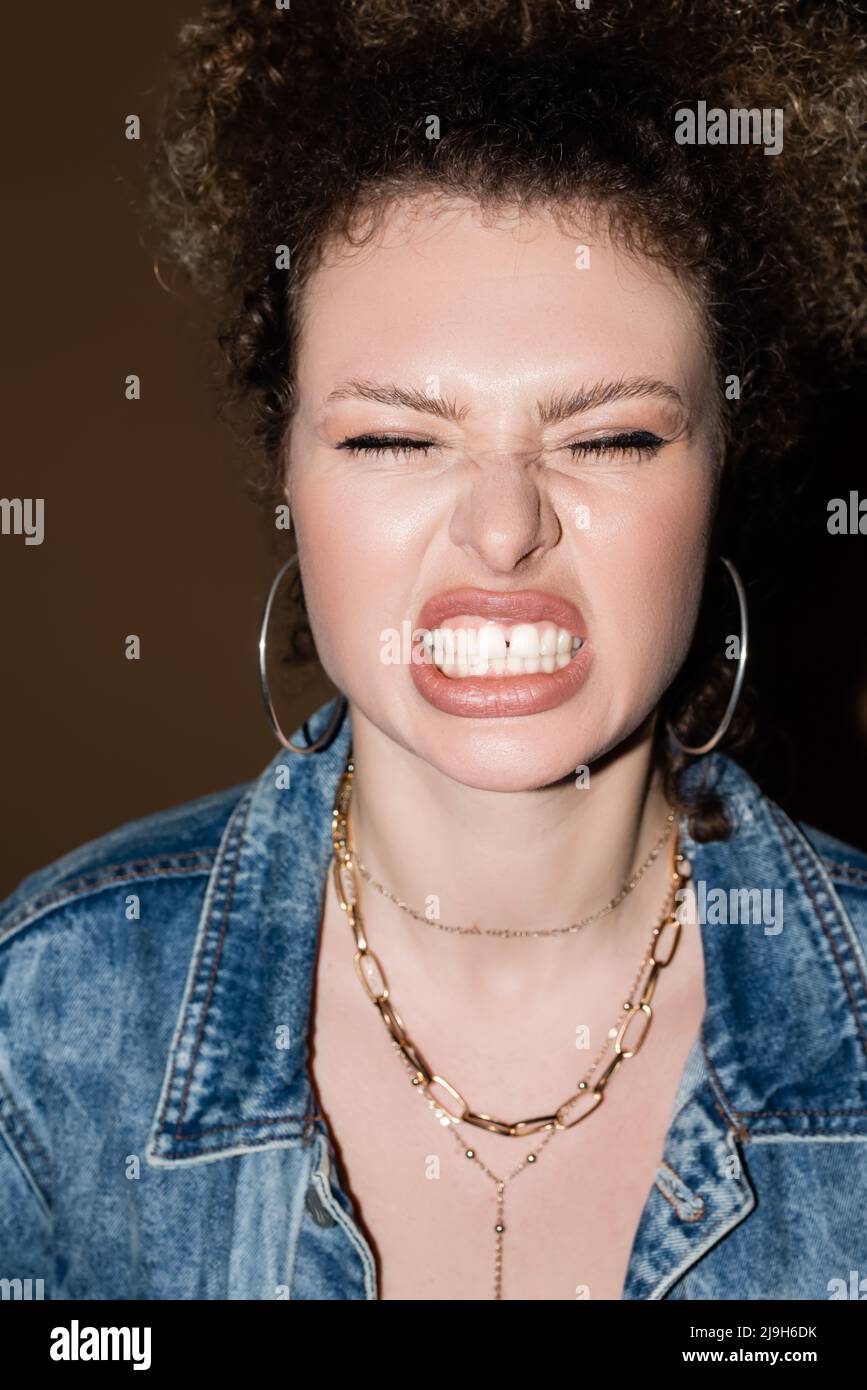 Angry model in denim jacket and accessories showing teeth on black ...
